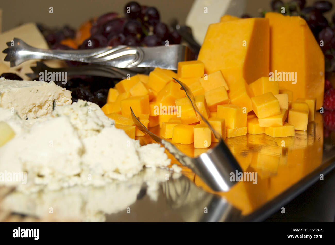 Close up of buffet table focusing on cubed orange cheddar cheese with ...