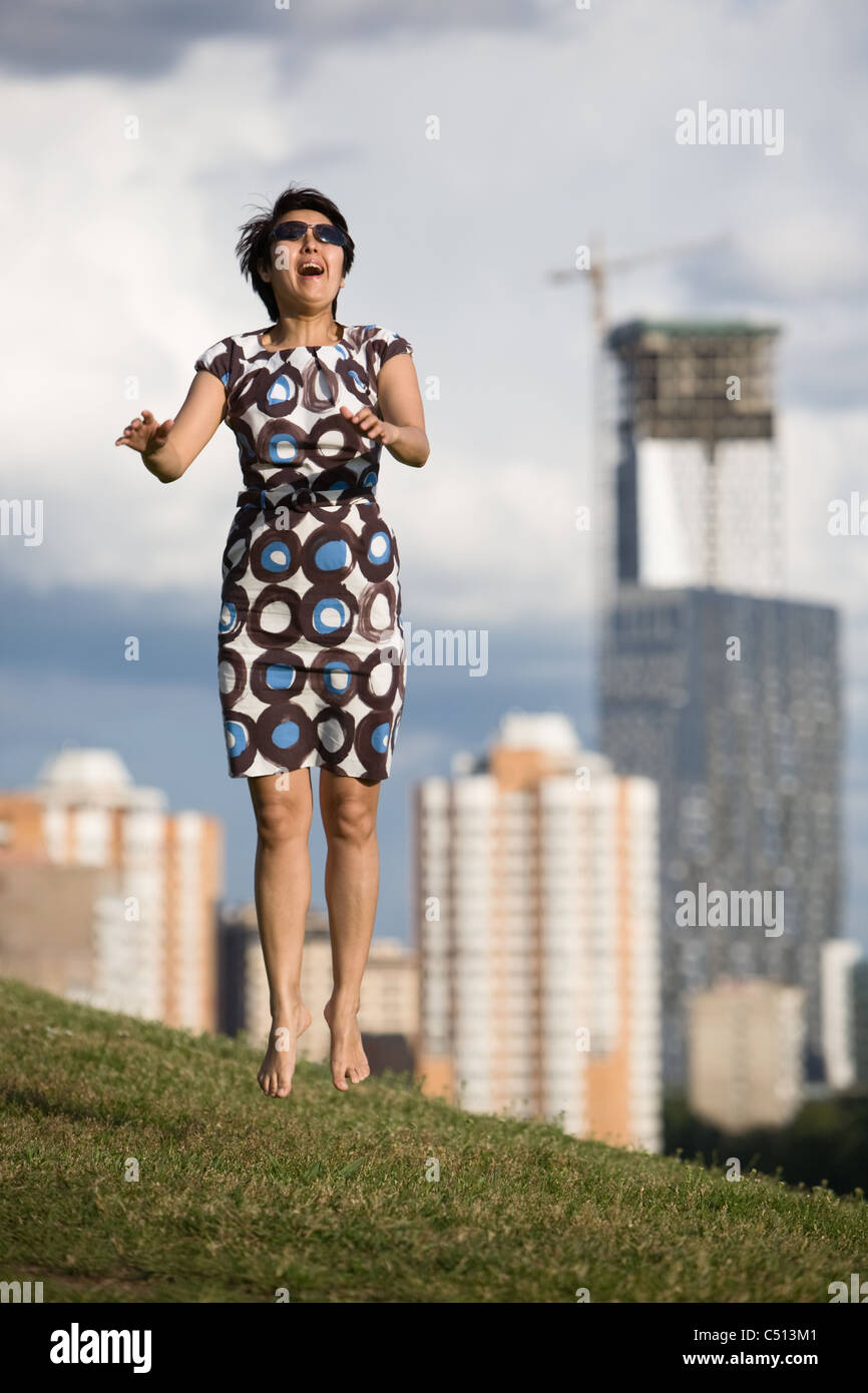 Woman jumping in air, skyscraper on background Stock Photo - Alamy