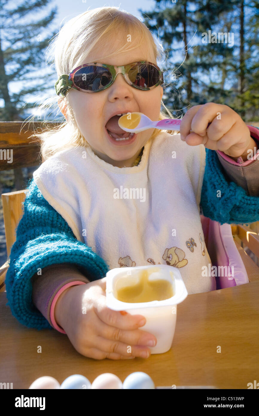 Baby girl eating yogurt with spoon Stock Photo - Alamy