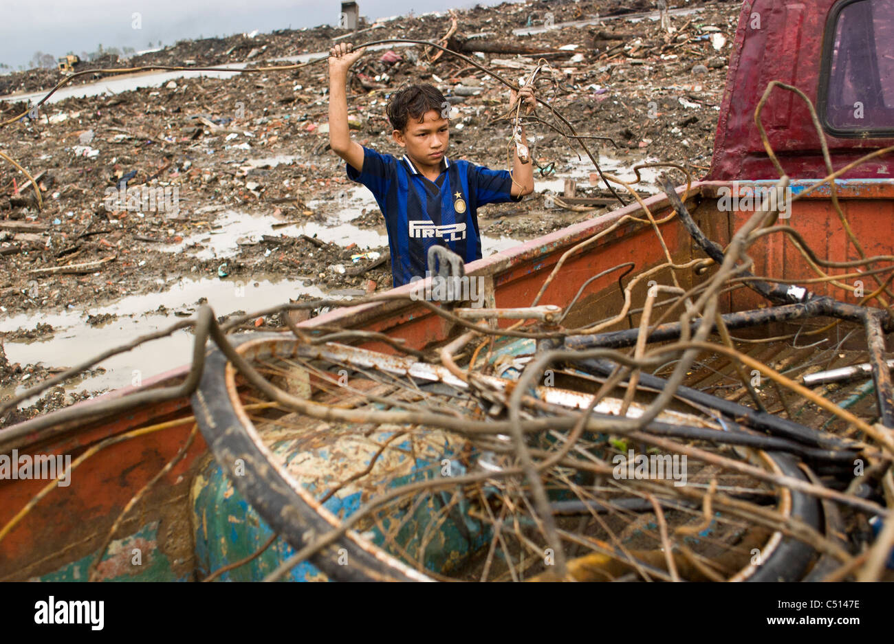 A boy collects scrap metal in the destruction caused by the earthquake ...