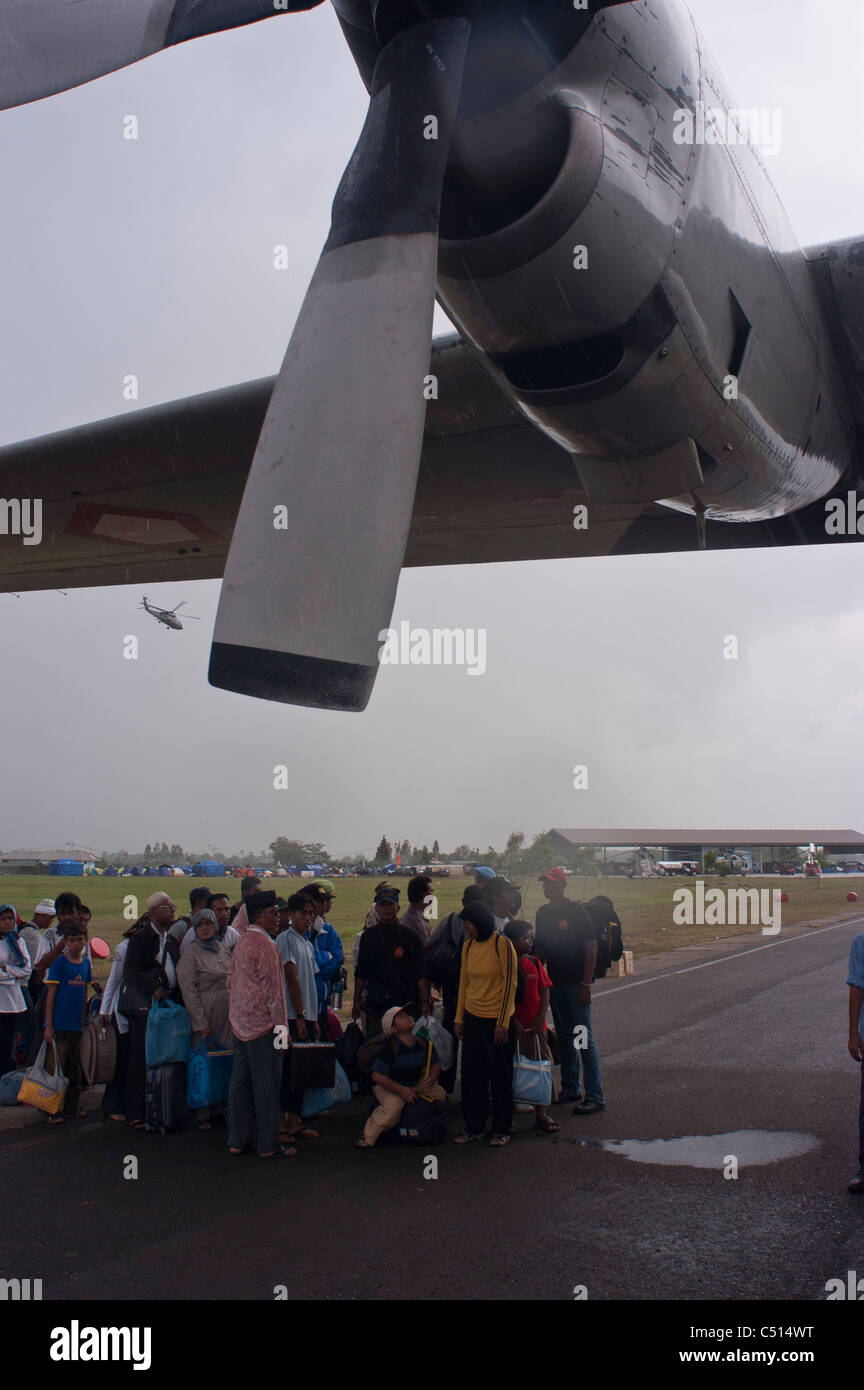 Refugees shelter under the wing of a transport plane bound for Medan ...