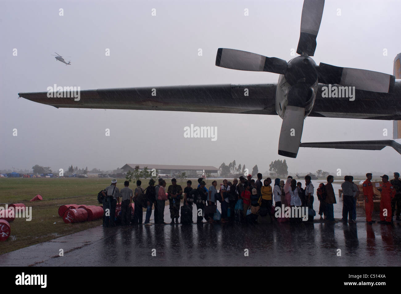 Refugees shelter under the wing of a transport plane bound for Medan ...