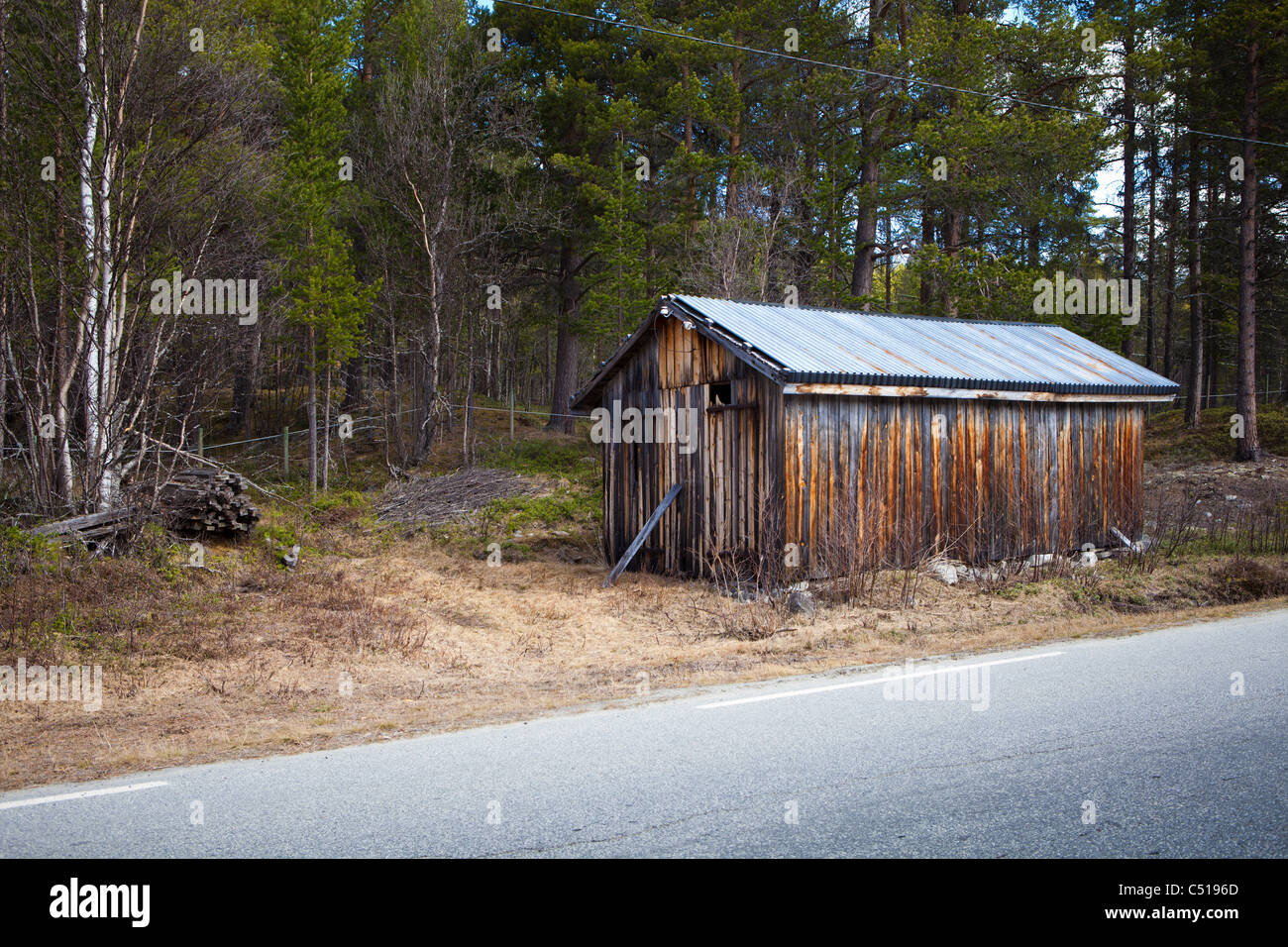 A rural shed on the side of a road surrounded by a forest Stock Photo ...