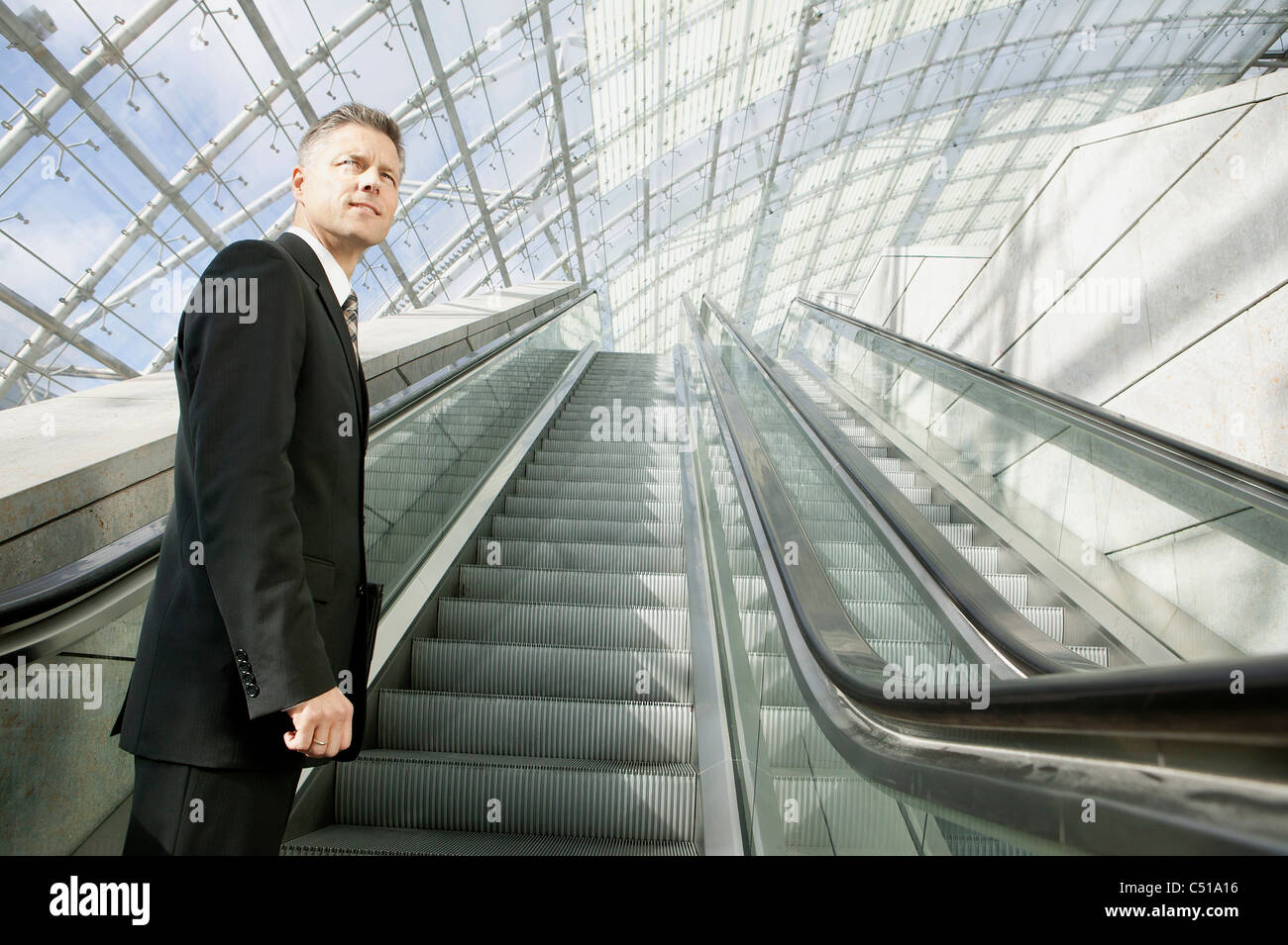 portrait of businessman on escalator Stock Photo - Alamy