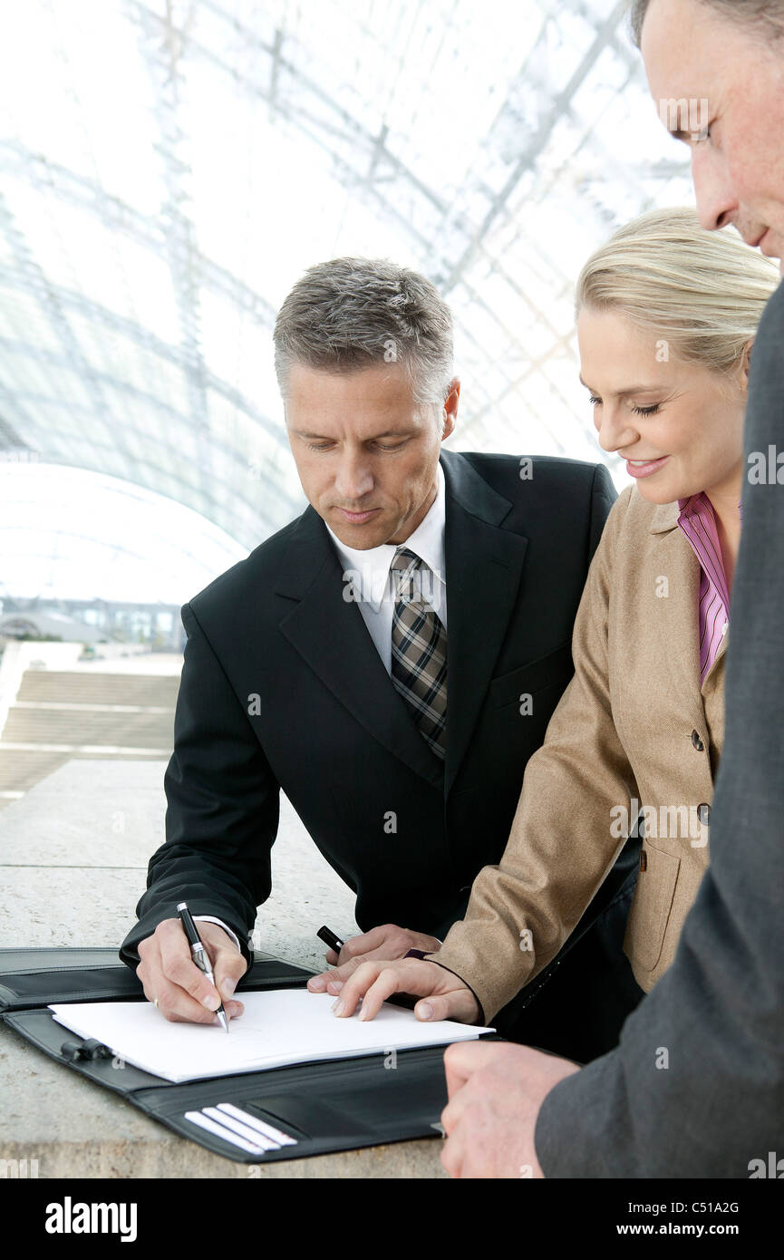 three business people signing document Stock Photo - Alamy three business people signing document Stock Photo - Alamy
