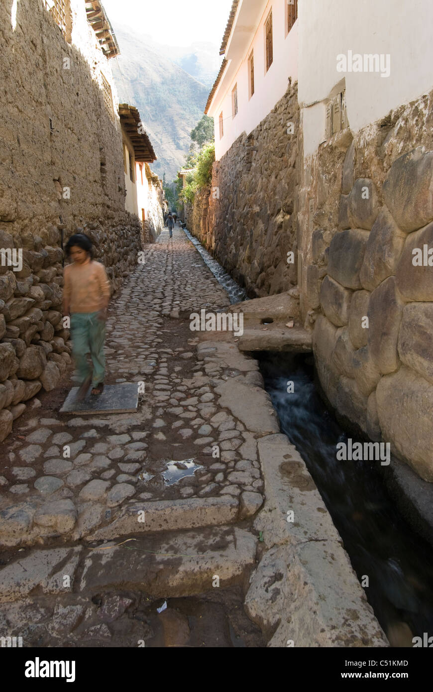 Young Peruvian girl walking down narrow street in Ollantaytambo near ...