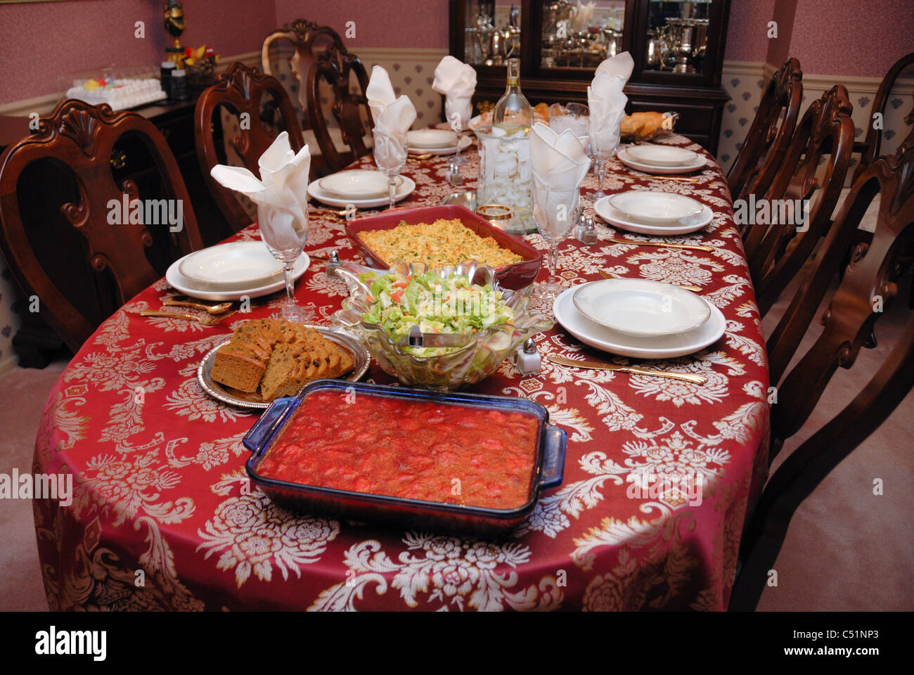 An elegant dining room's table is set for a holiday dinner, with place ...