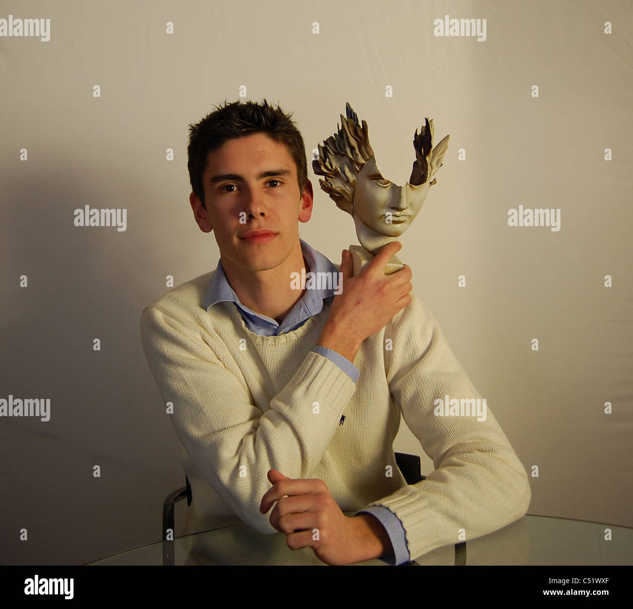 Young man smiling holding statuette of Apollo revealing his face ...