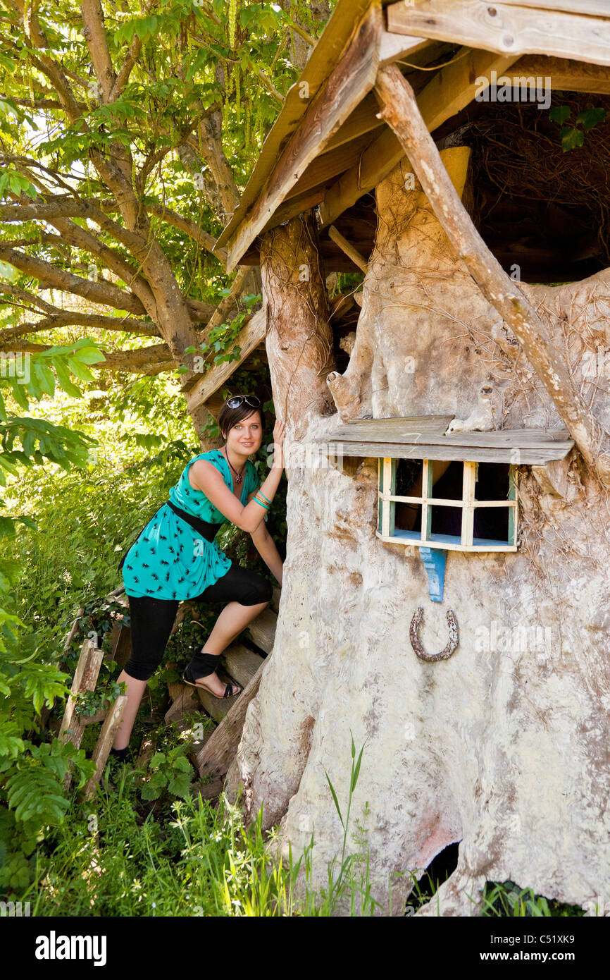 Young woman entering beautiful traditional tree or Wendy house built by ...