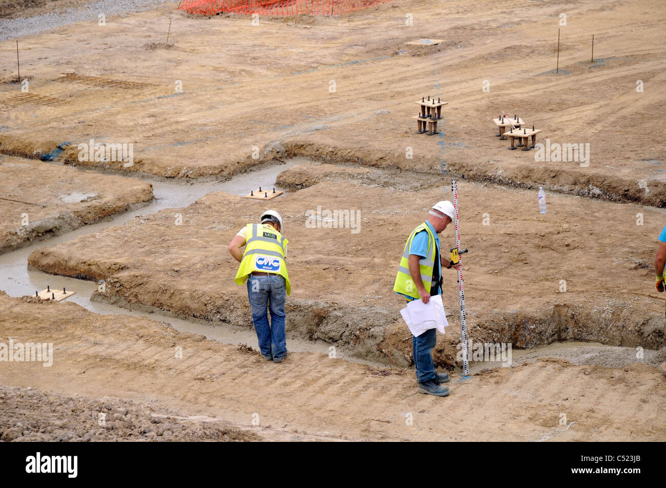 Building site showing strip foundation trenches and surveyors checking ...