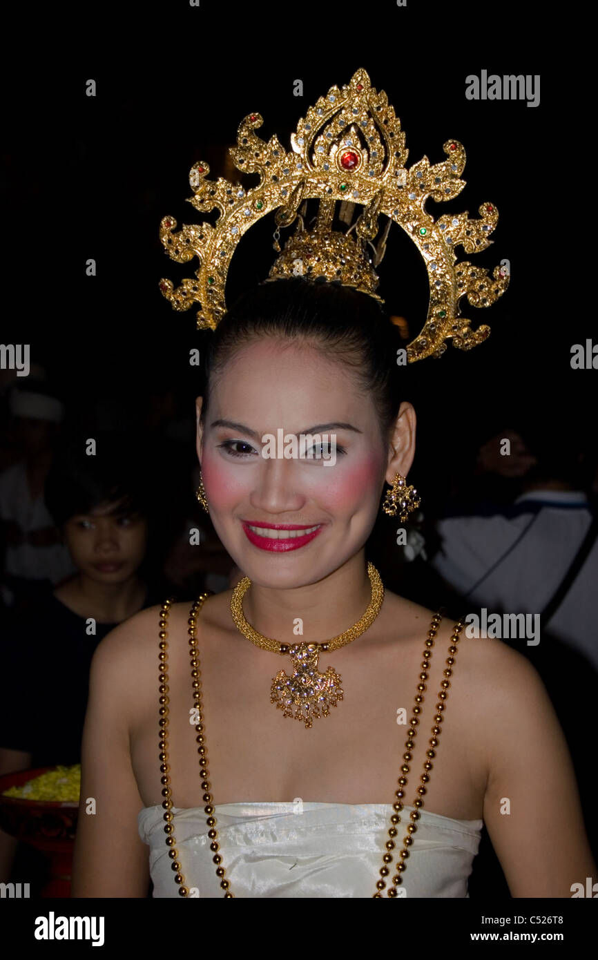 A traditionally costumed Thai woman is wearing a bright gold crown at a ...