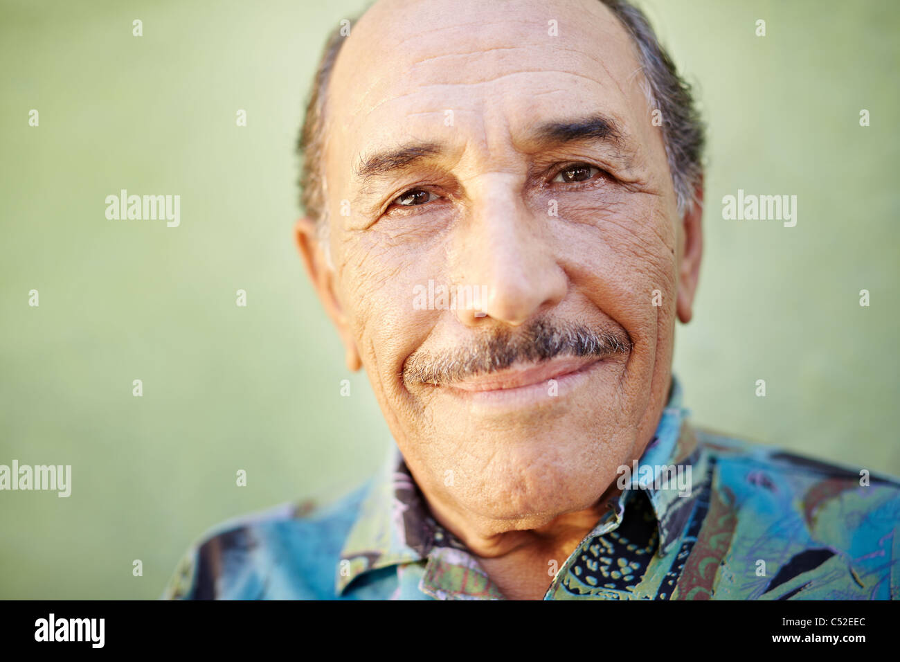 portrait of senior hispanic man with mustache looking at camera against ...