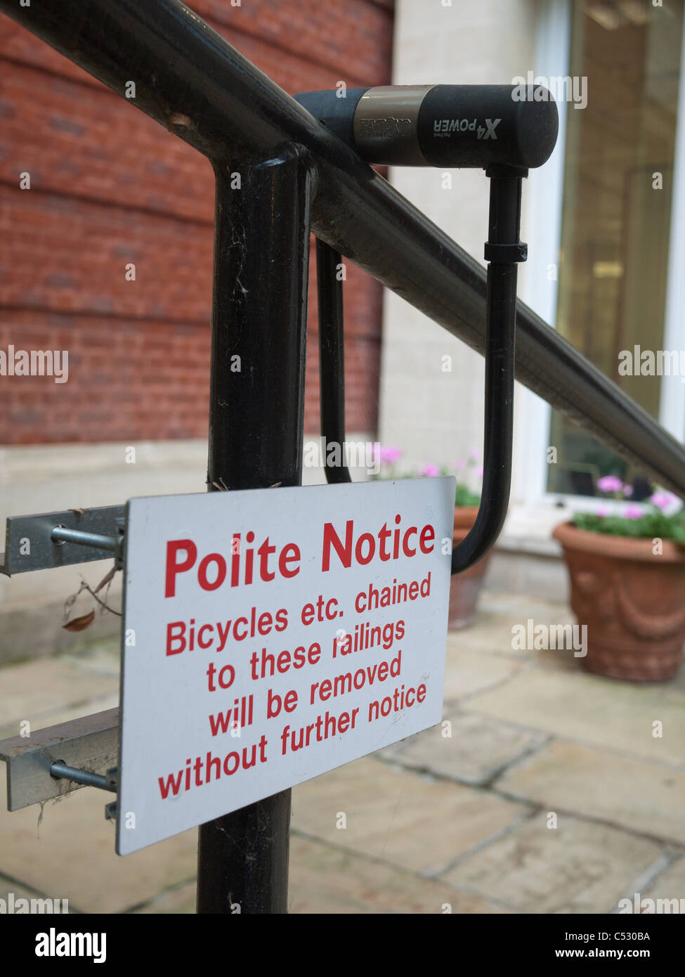 Notice saying bicycles will be removed with bicycle lock attached Stock ...