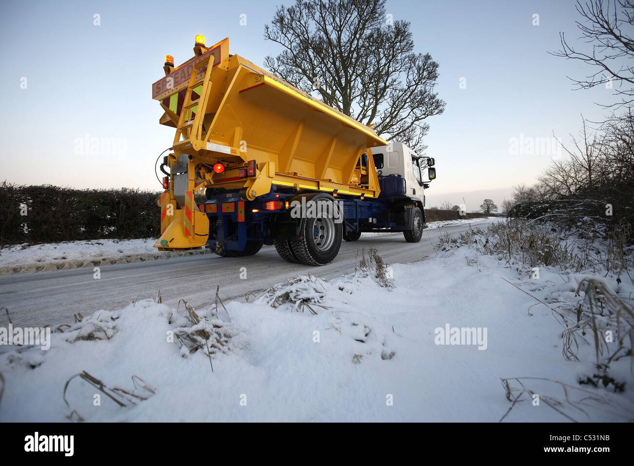 Gritter spreading grit over a snow covered lane, UK Stock Photo - Alamy
