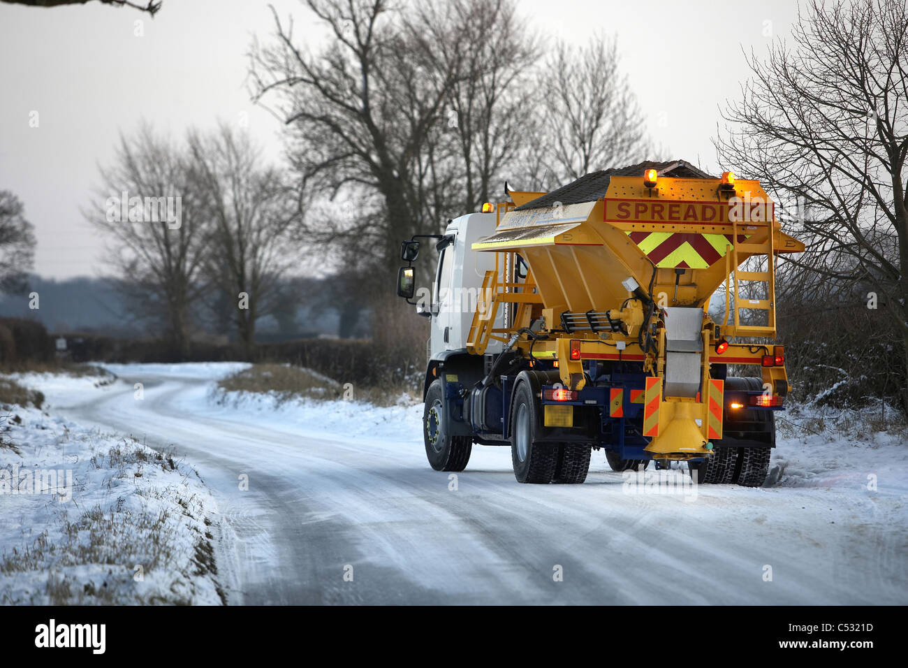 Gritter spreading grit over a snow covered lane, UK Stock Photo - Alamy