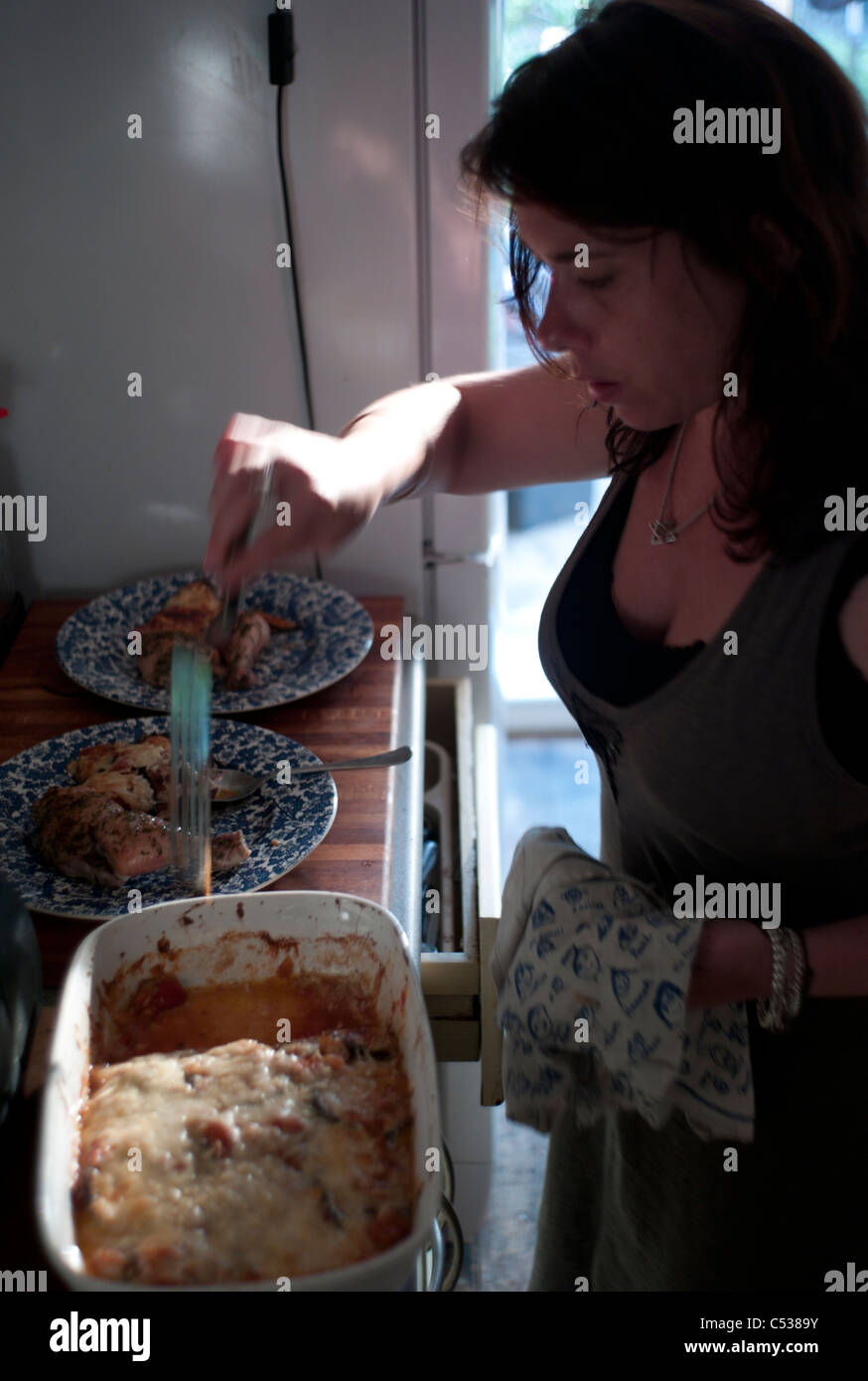 Woman in the kitchen serving up dinner in lovely evening sunlight Stock ...