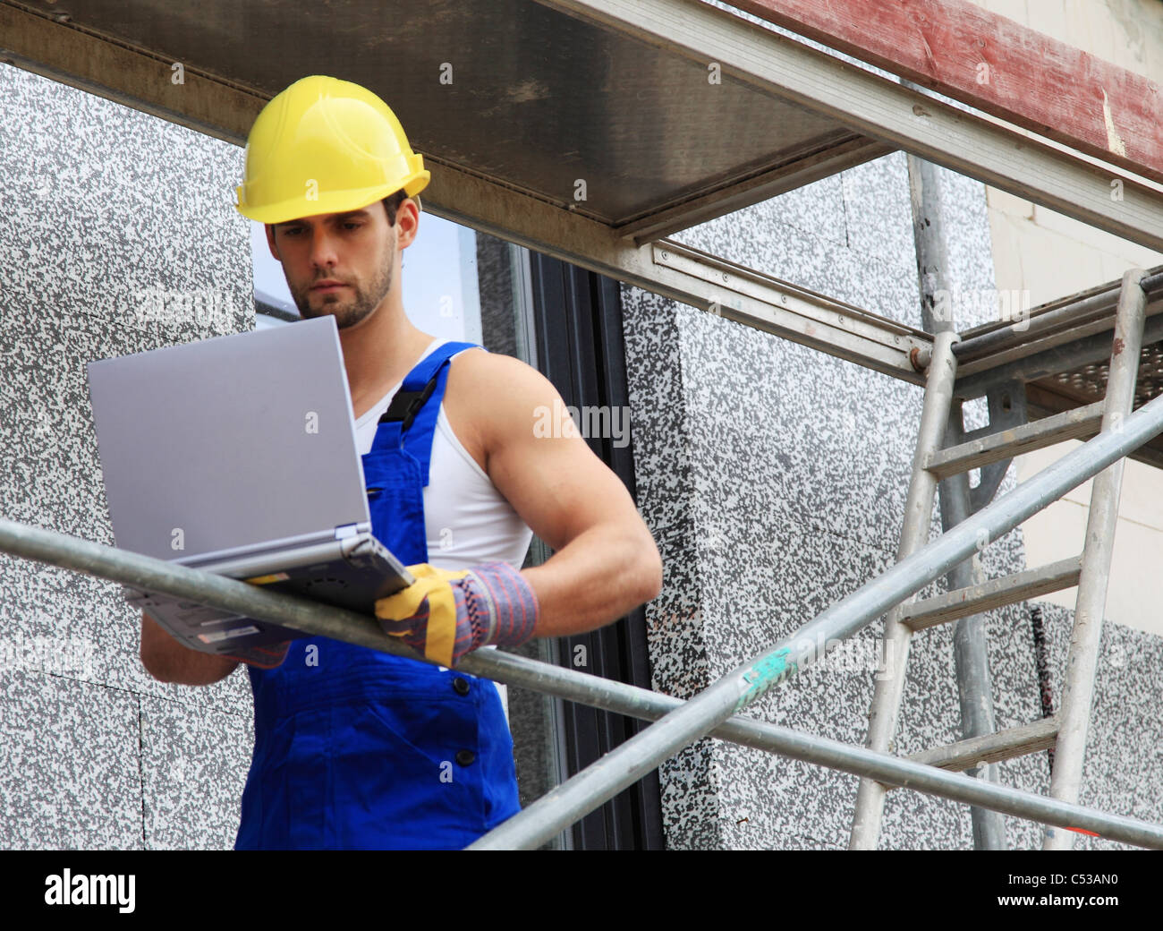 Manual worker on construction site using laptop Stock Photo - Alamy