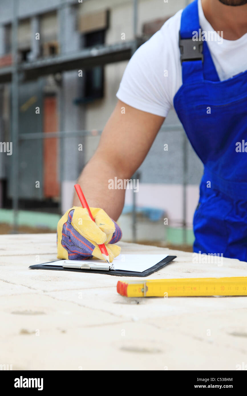 Manual worker on construction site writing on clipboard Stock Photo - Alamy
