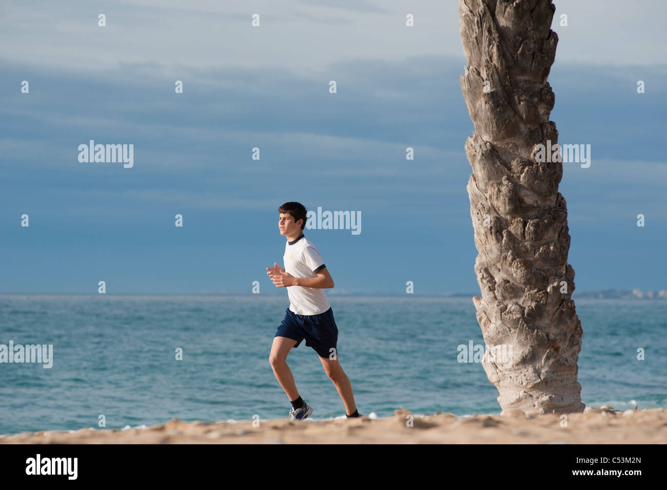 Fit teenager jogging early morning on the beach Stock Photo - Alamy