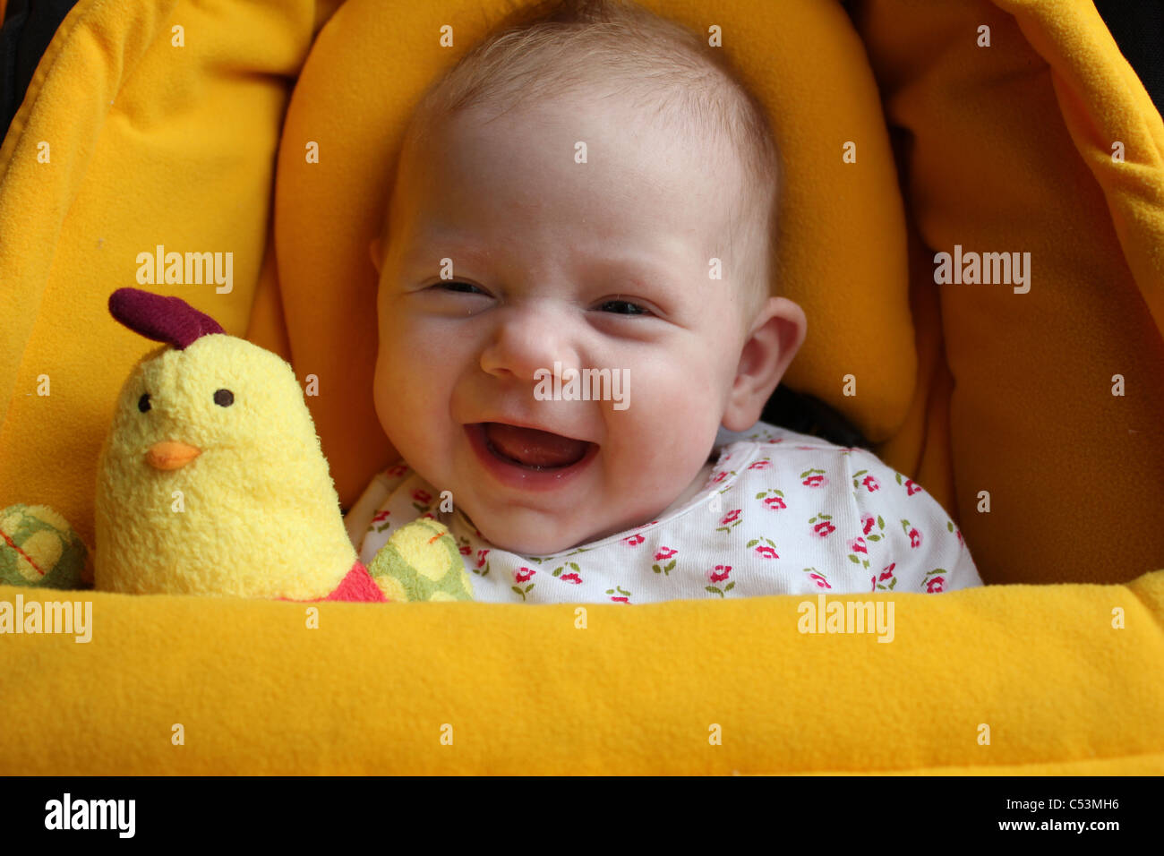Three month old baby girl smiling in buggy with toy chick Stock Photo ...