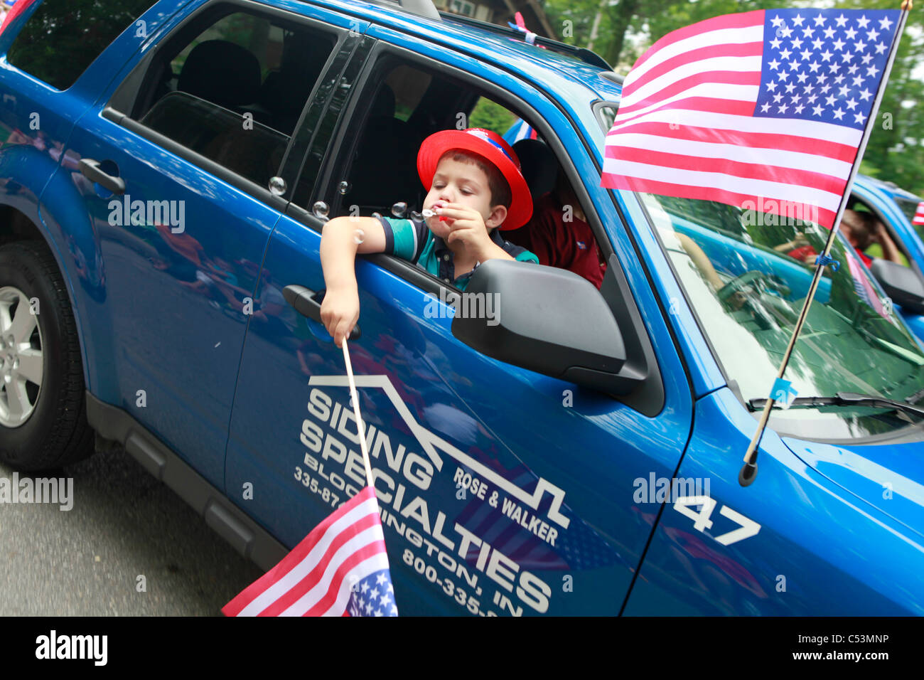 Boy blowing bubbles holding American flag during 4th of July Parade ...