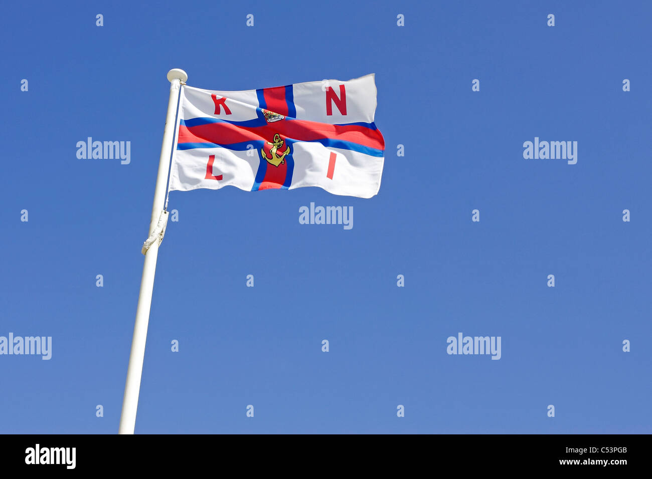 An RNLI flag flying against a blue sky Stock Photo - Alamy