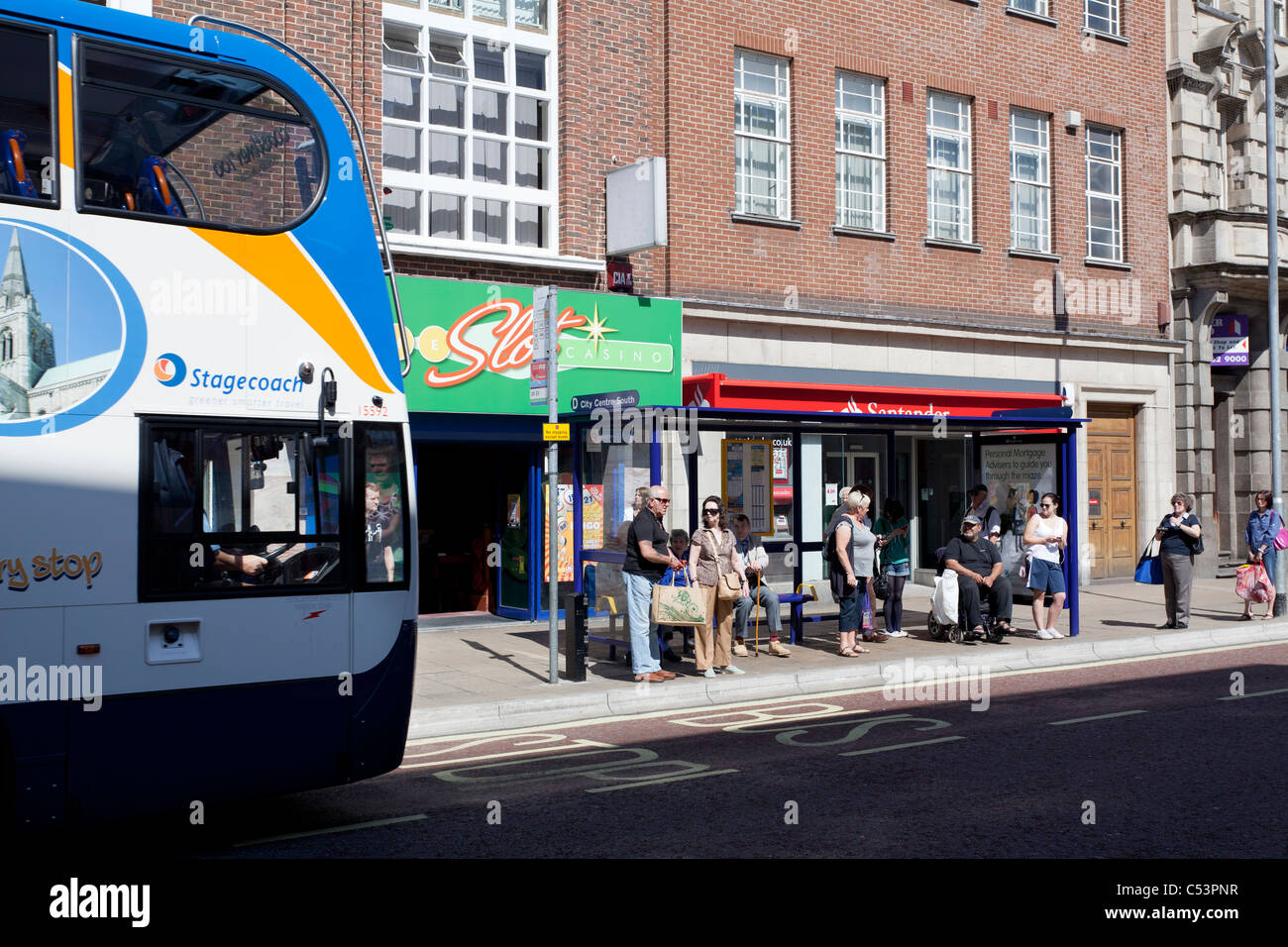 bus approaching queueing passengers at bus stop Stock Photo - Alamy