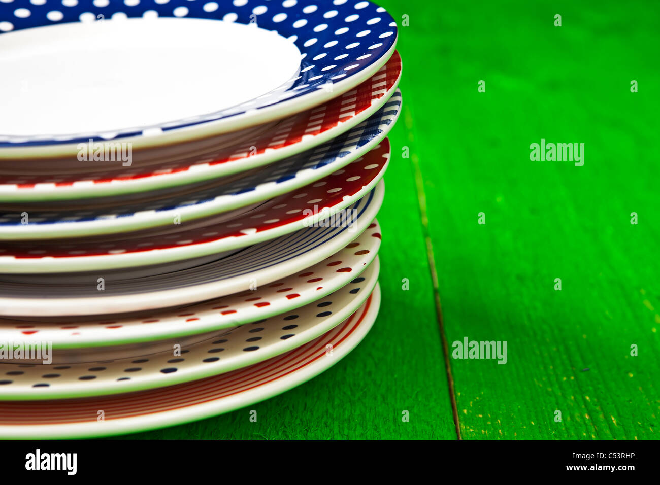 rustic and colorful plates on a green wooden table Stock Photo - Alamy