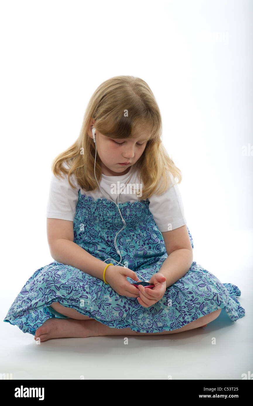 A young girl of 7 or 8 years listening to an ipod Nano/MP3 player ...