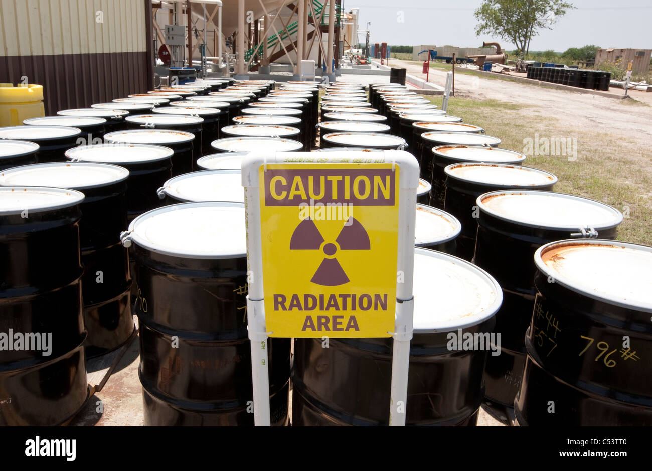 Sign cautioning of radiation in from of rows of barrels containing ...