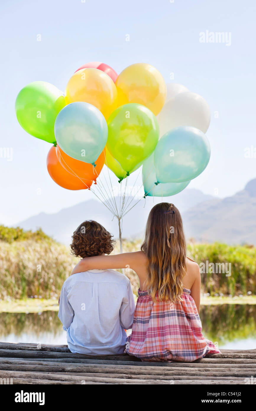 Rear view of siblings playing with balloons at a pier Stock Photo - Alamy