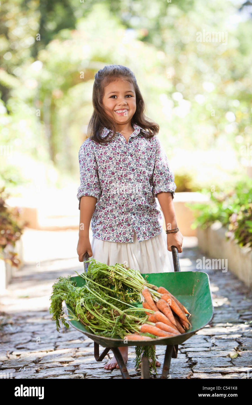 Cute girl pushing a wheelbarrow filled with carrots Stock Photo - Alamy