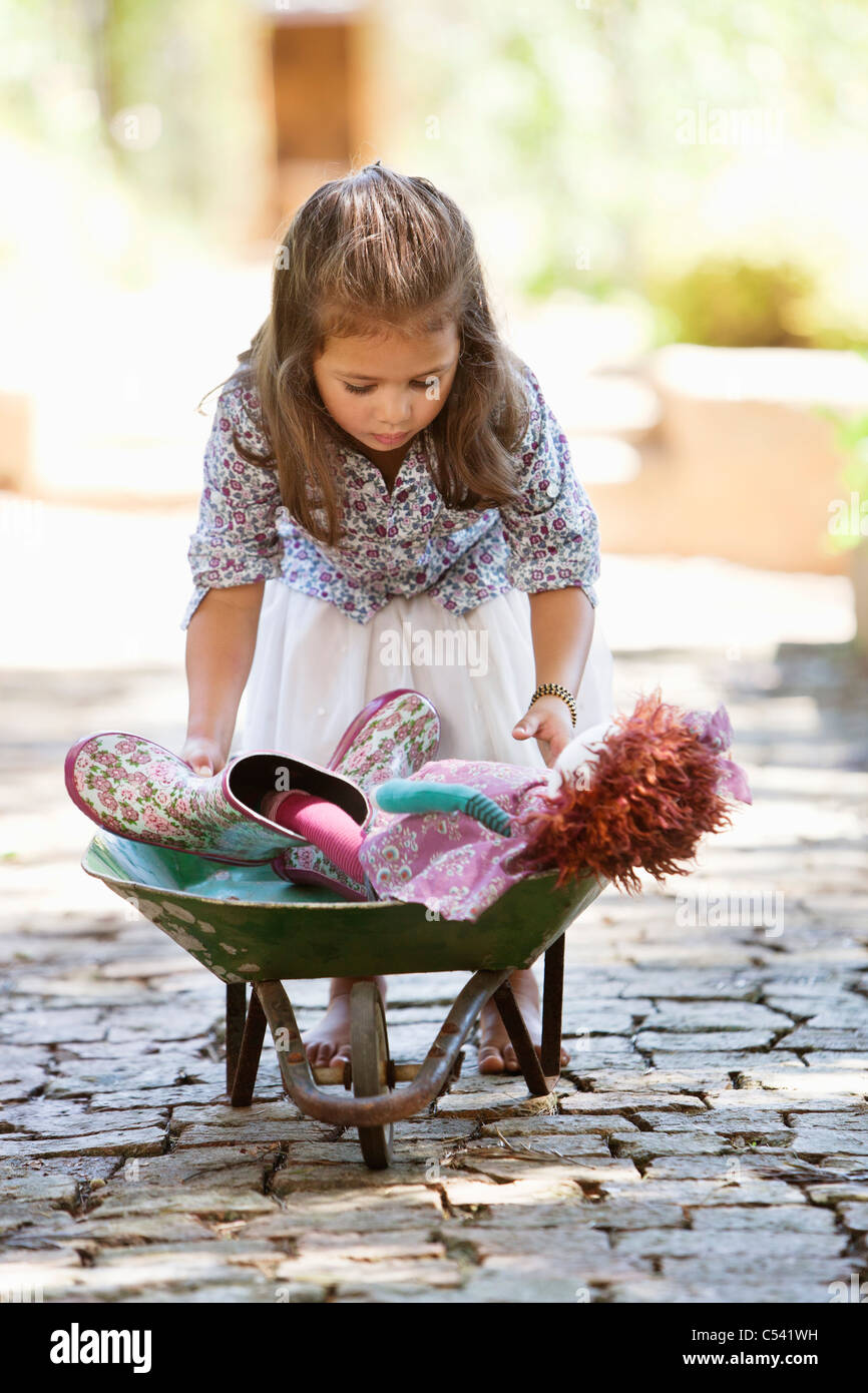 Cute girl pushing a wheelbarrow filled with toys Stock Photo - Alamy