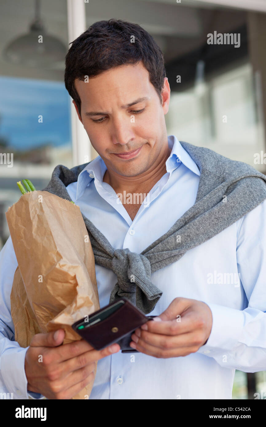 Mid adult man checking the empty wallet with paper bag full of ...