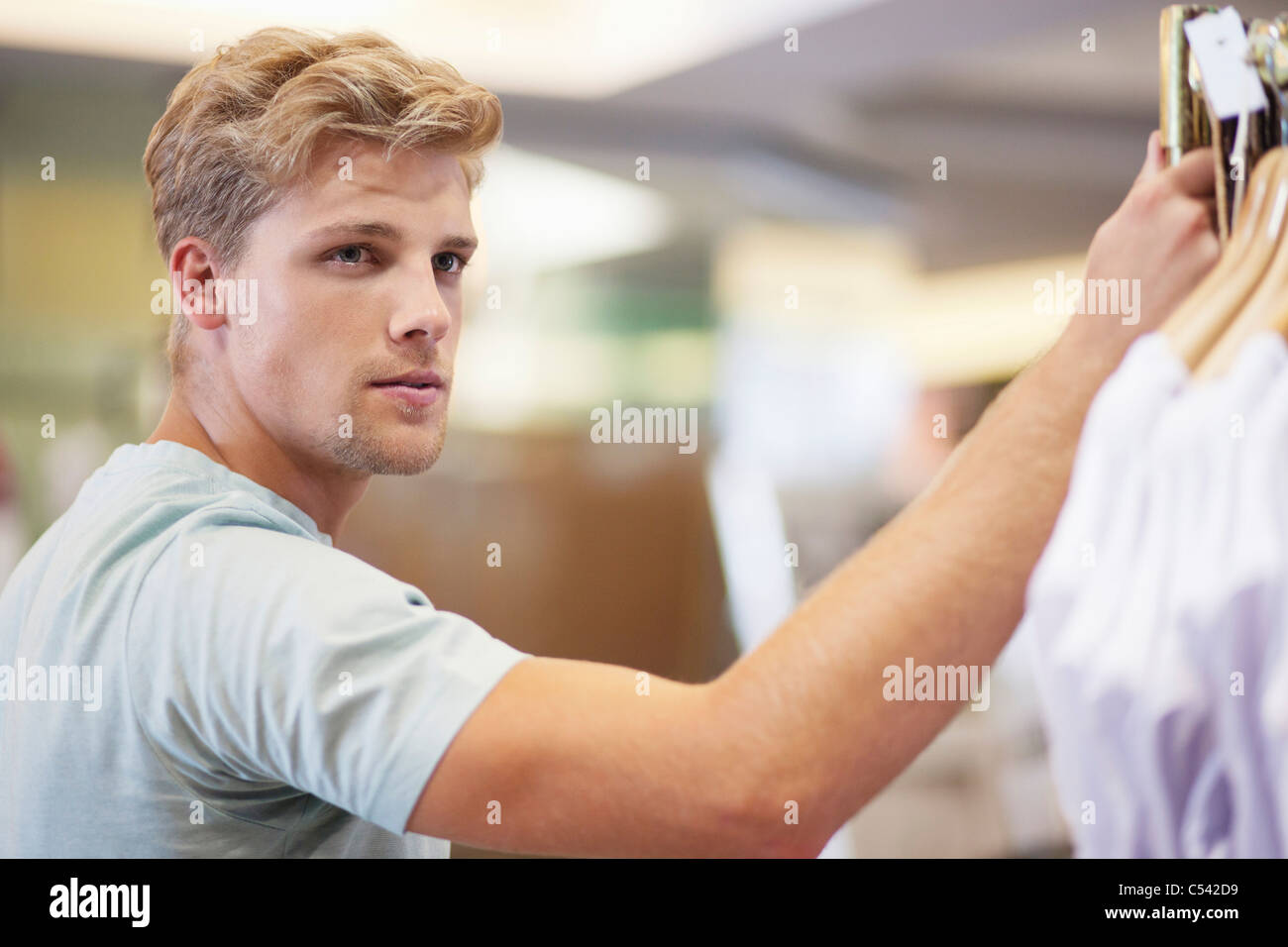 Young man standing in a clothing store Stock Photo - Alamy