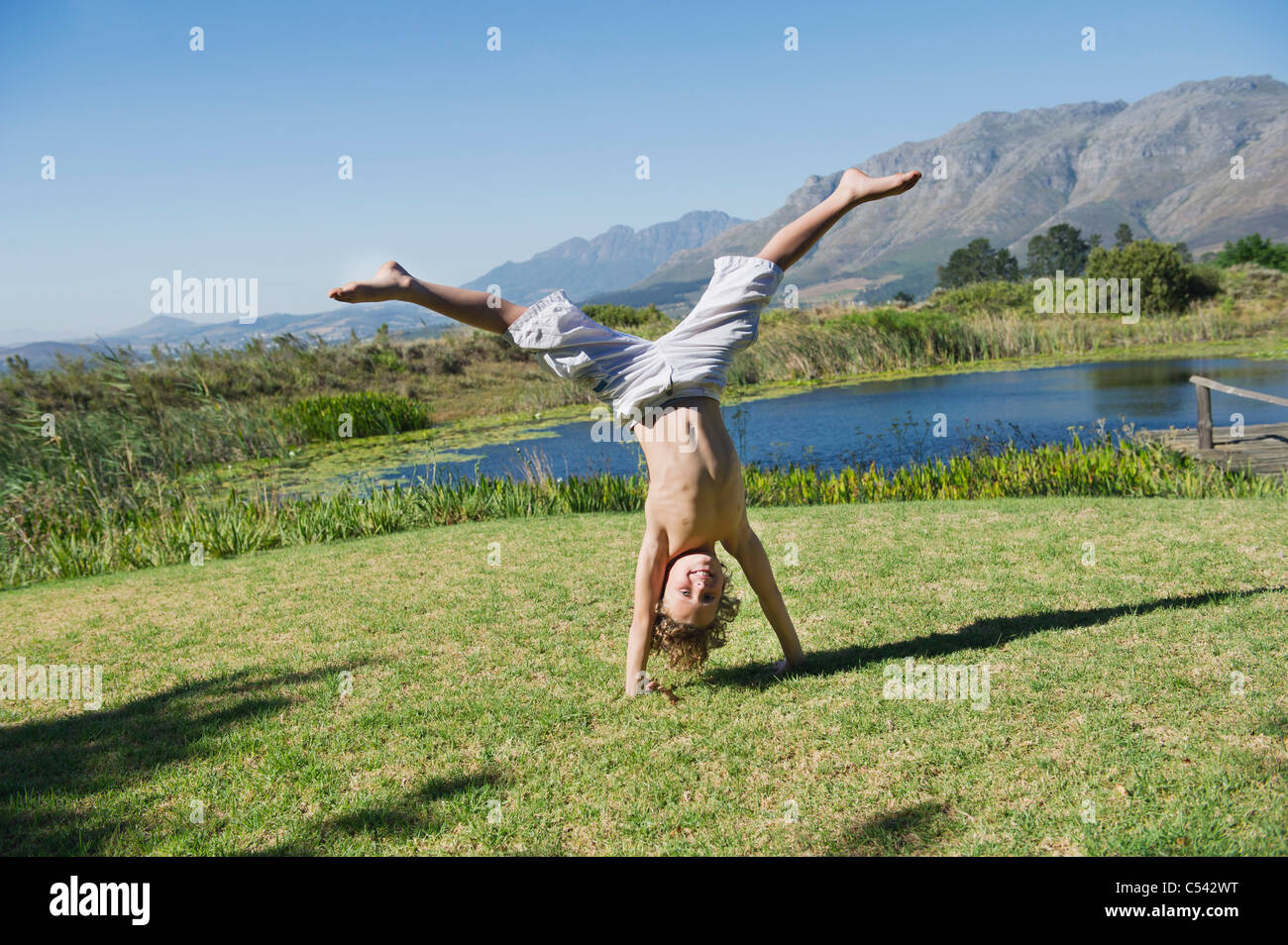 Cute little boy doing cartwheel against mountain Stock Photo - Alamy