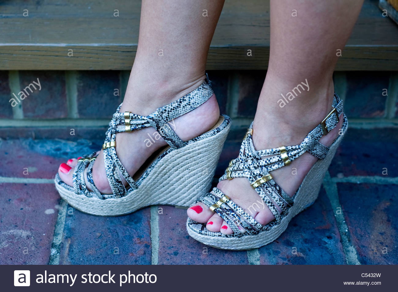 A pair of ladies fashionable wedge sandals worn with red painted Stock ...