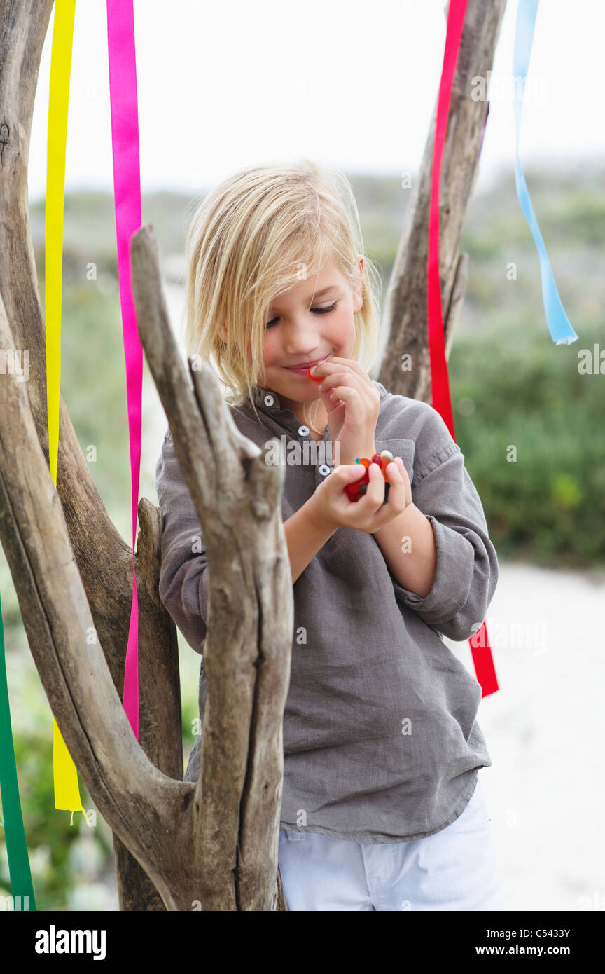 Girl leaning against a tree and eating fruit Stock Photo - Alamy