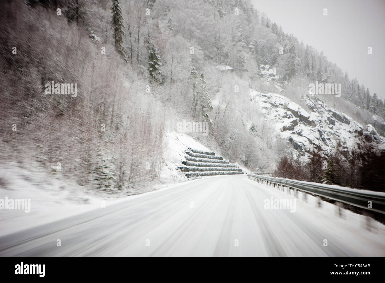 Winter woodland mountain road with rocky sides is blurred and in the ...