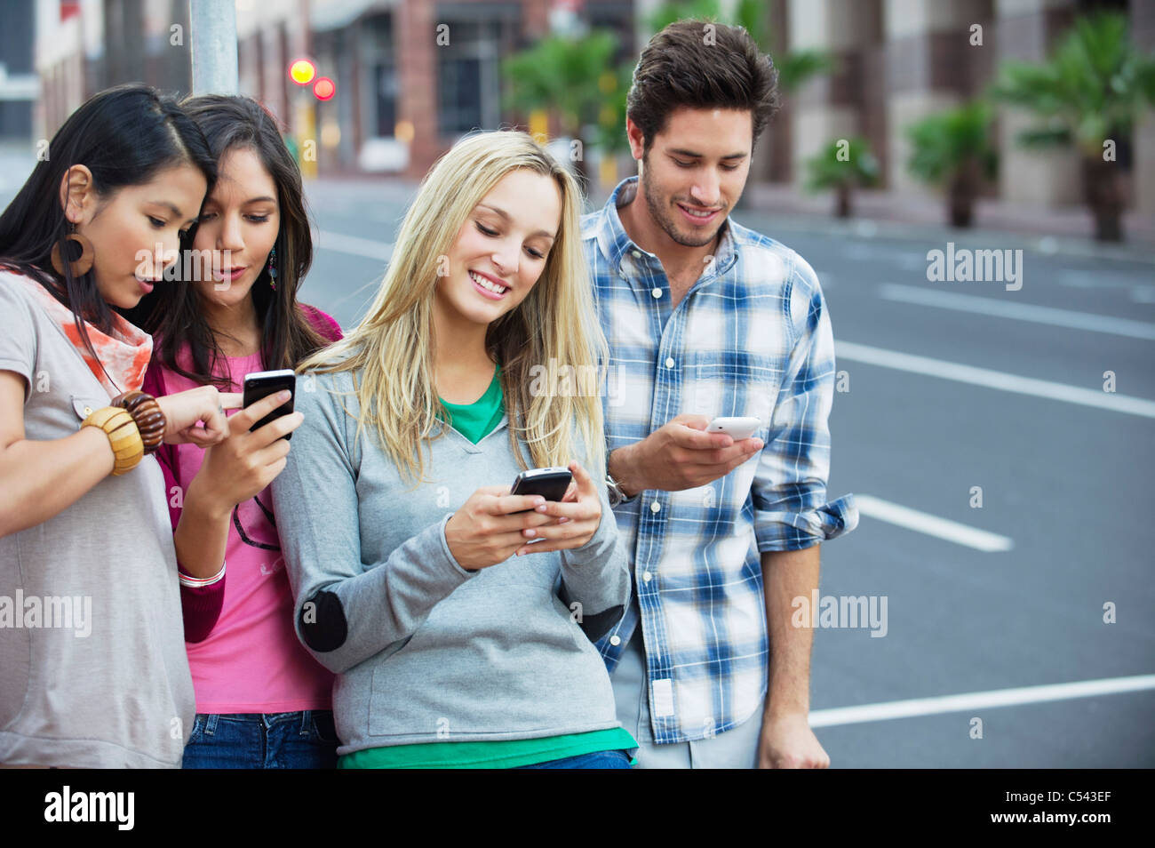 Friends using mobile phones outdoors Stock Photo - Alamy