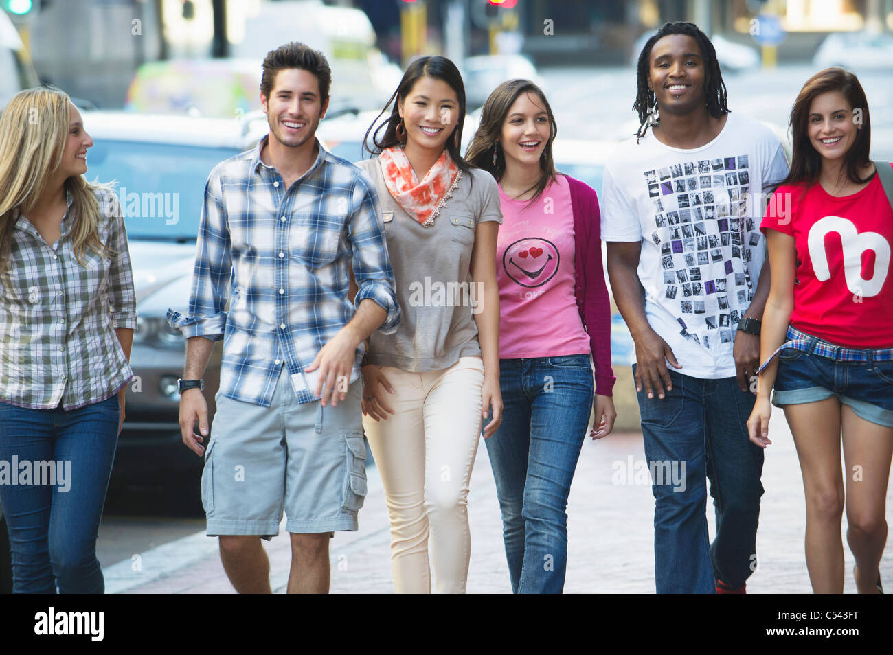 Friends walking on the sidewalk against cars Stock Photo - Alamy