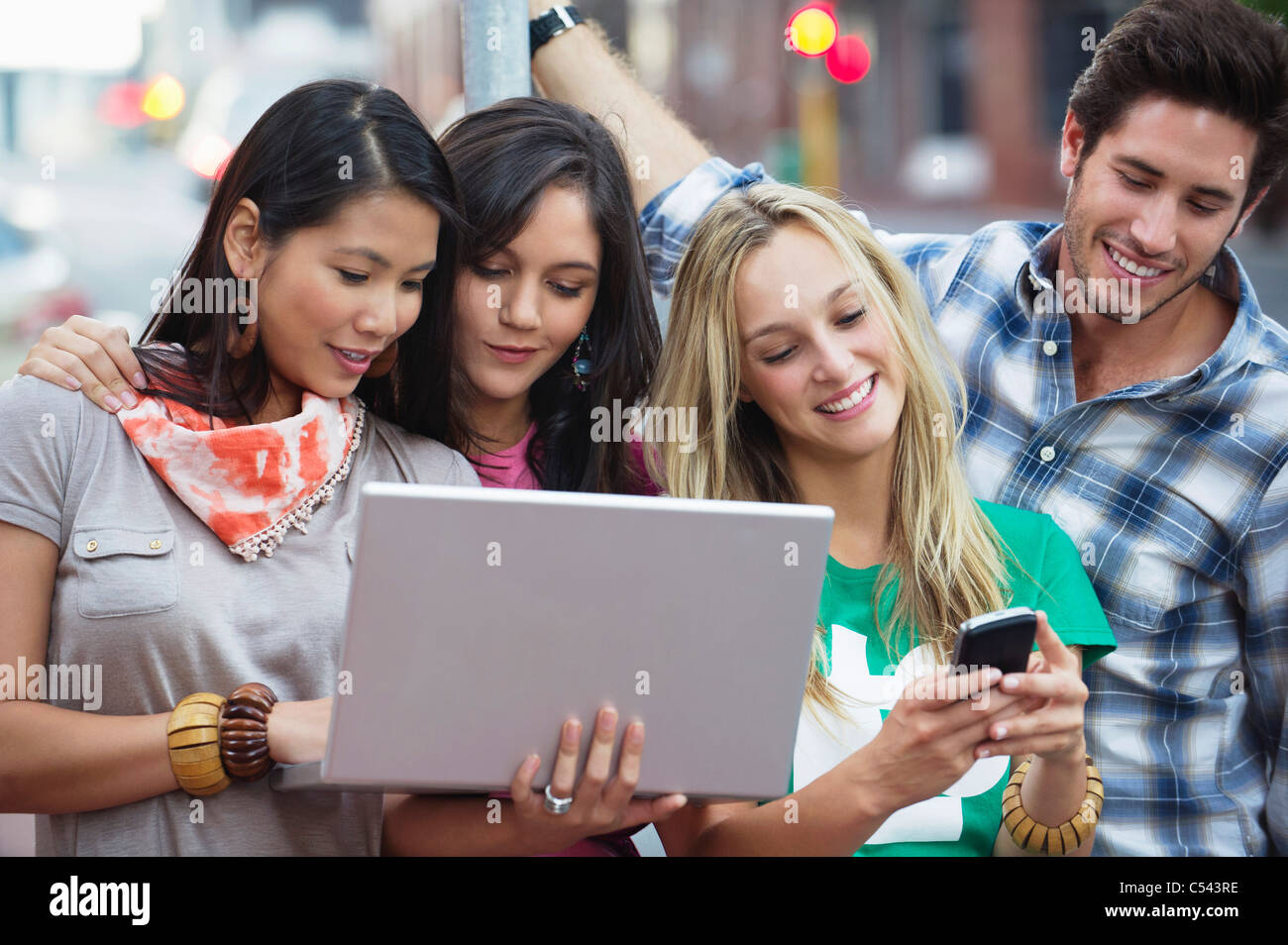 Friends using electronic gadgets outdoors Stock Photo - Alamy