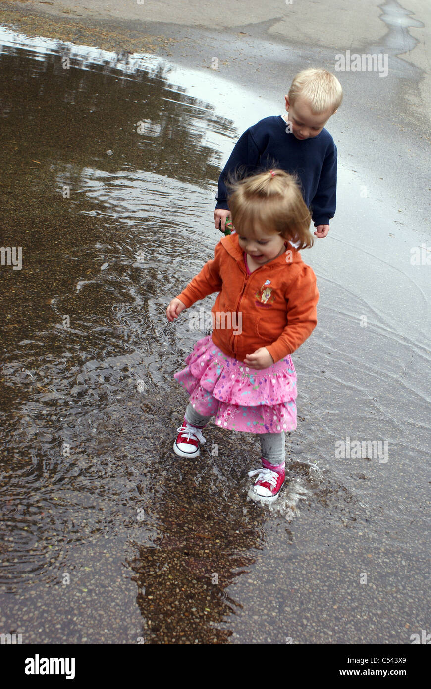 Kids playing and splashing in a puddle Stock Photo - Alamy