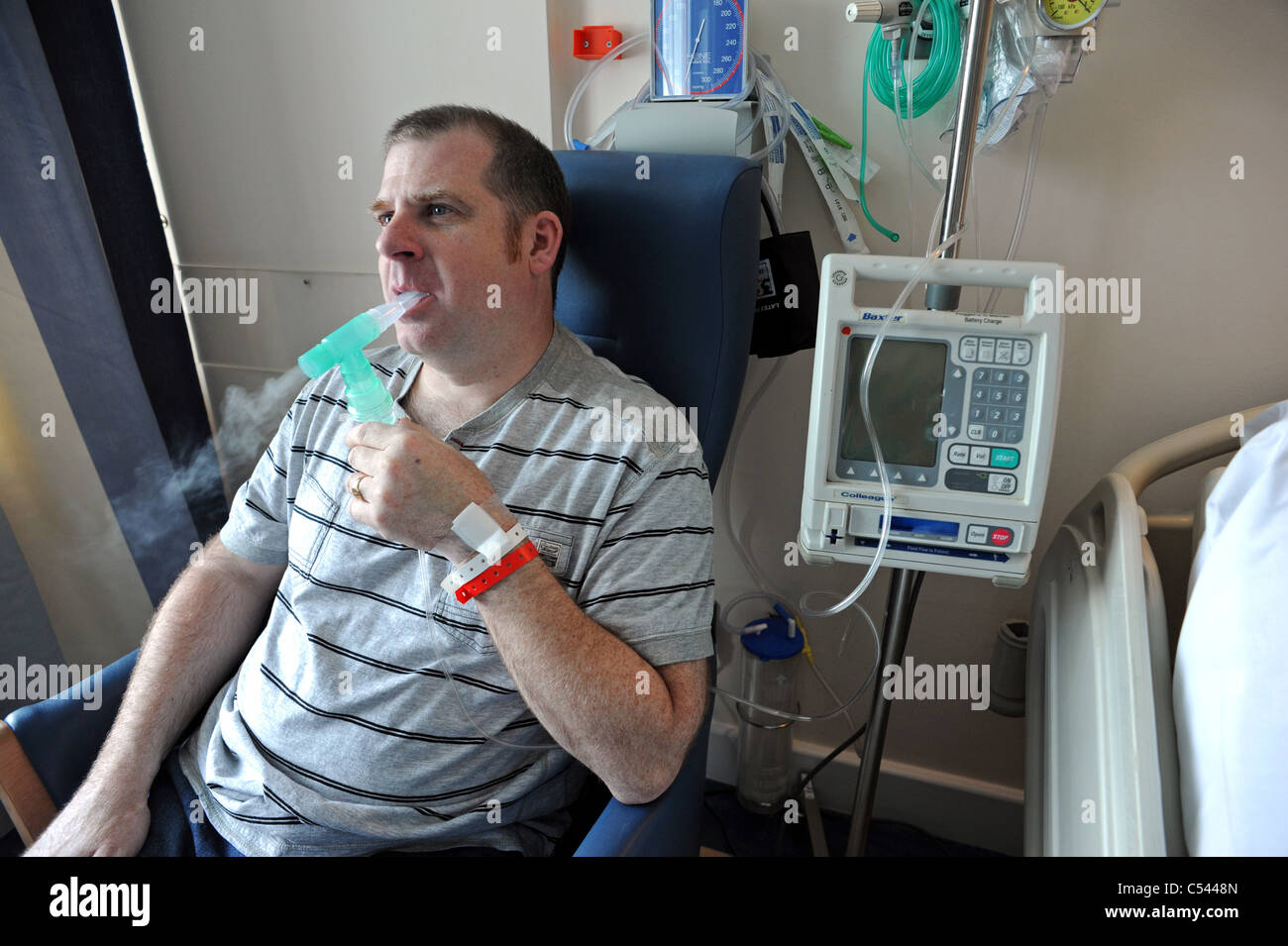 A man inhales on a nebuliser to help with his breathing in his room in ...