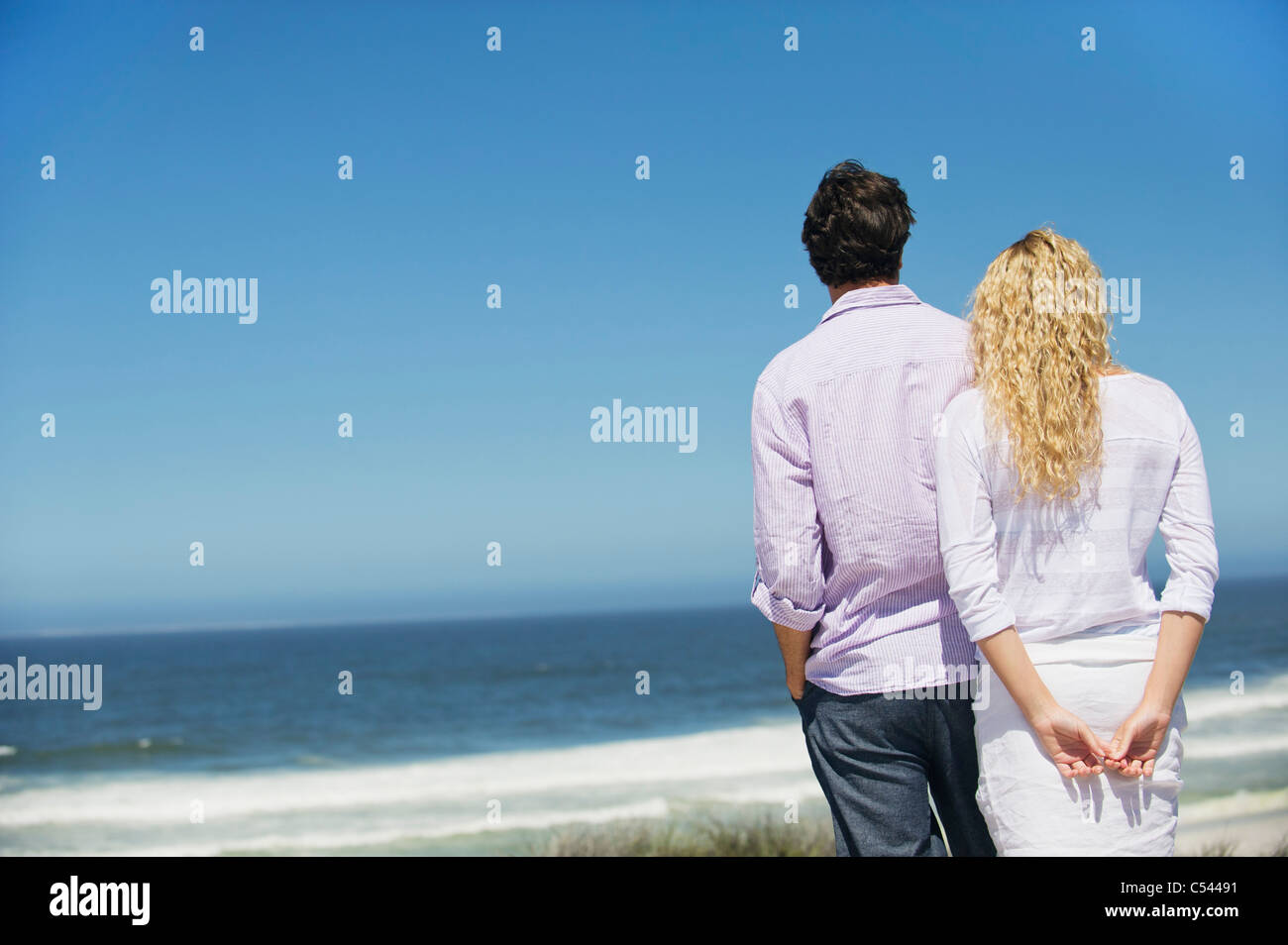 Rear view of a couple looking at sea Stock Photo - Alamy