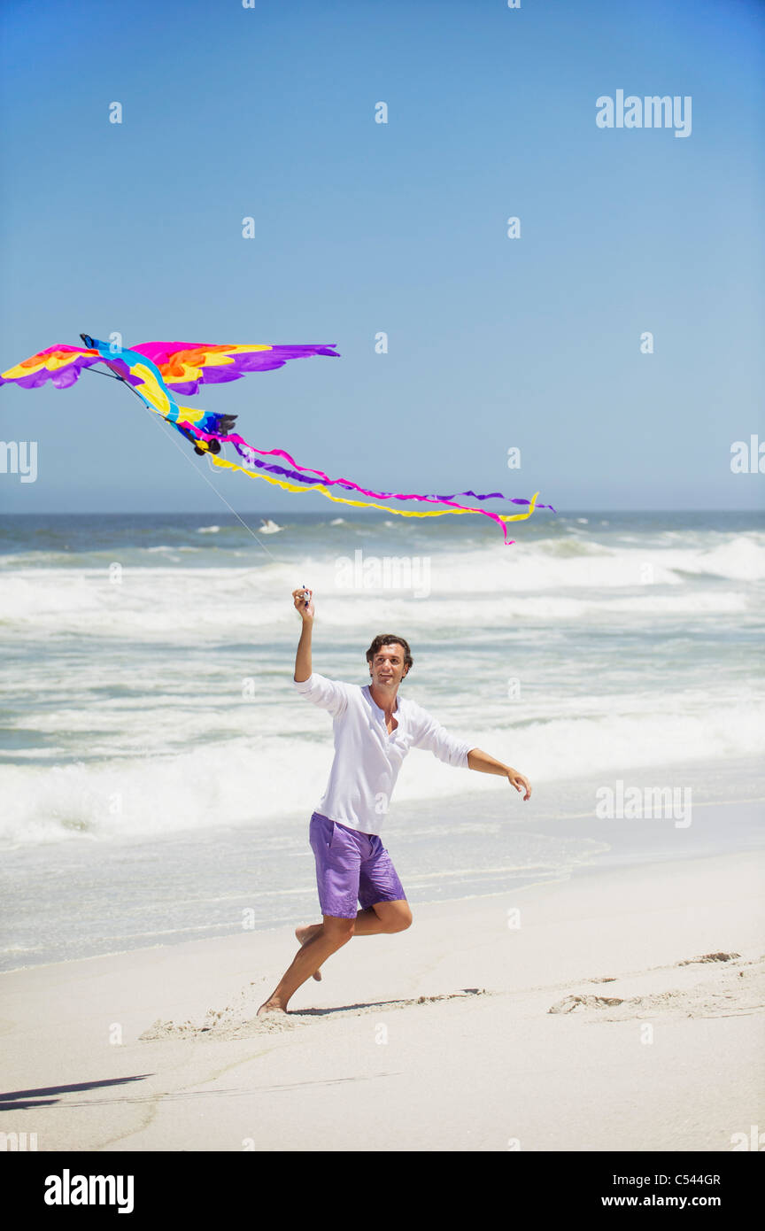 Mid adult man flying kite on the beach Stock Photo - Alamy