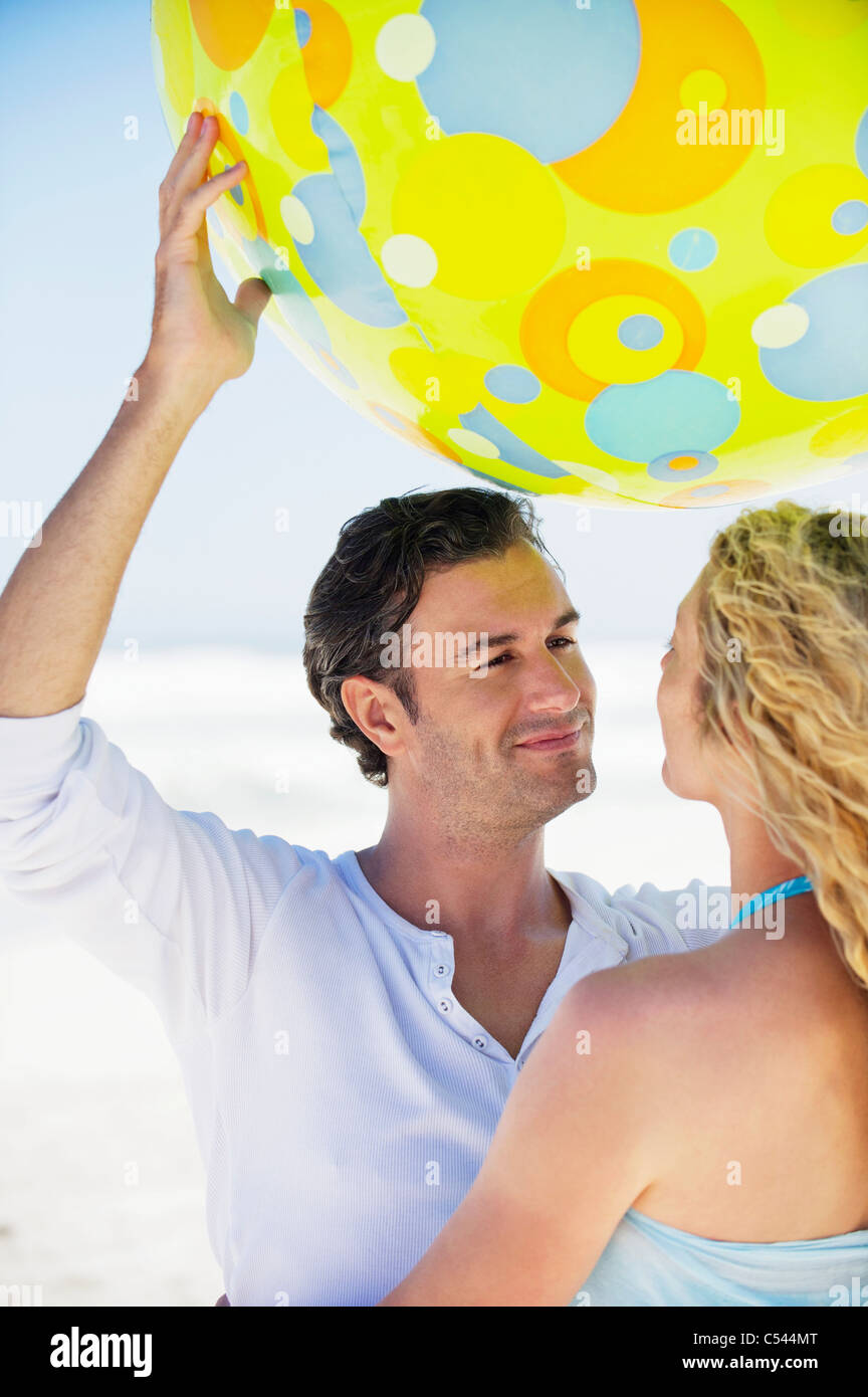 Man lifting a beach ball with a woman near him Stock Photo - Alamy