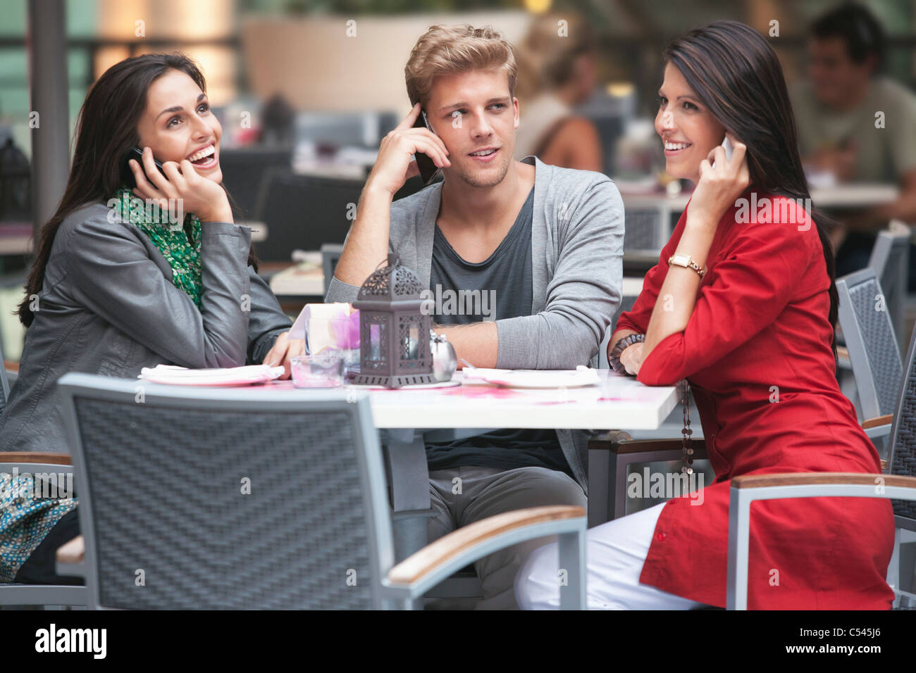 Three young friends talking on mobile phones in a restaurant Stock ...