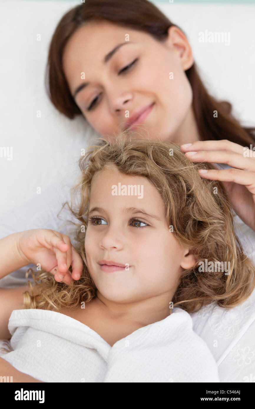 Young woman and little girl wrapped in white towel lying in bedroom ...