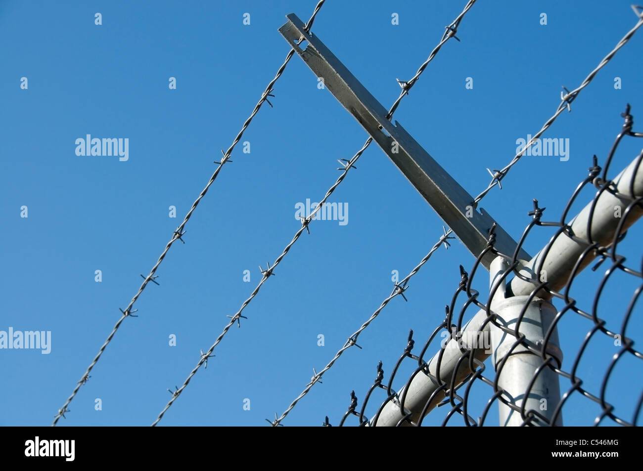 Low angle view of a portion of a chain-link fence with rows of barbed ...
